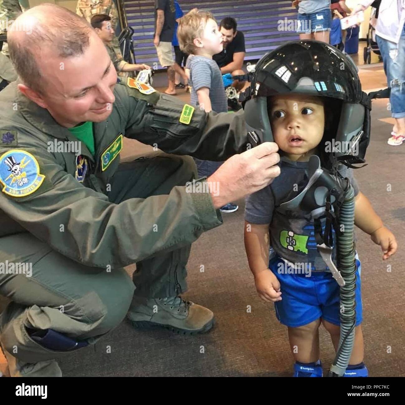 Lt. Col. Scott Sieting, 310th Fighter Squadron pilot, helps a child try ...