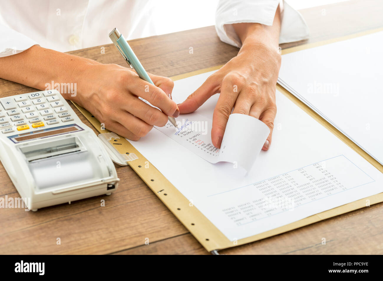 Female accountant calculating and reviewing numbers on a receipt as she ...