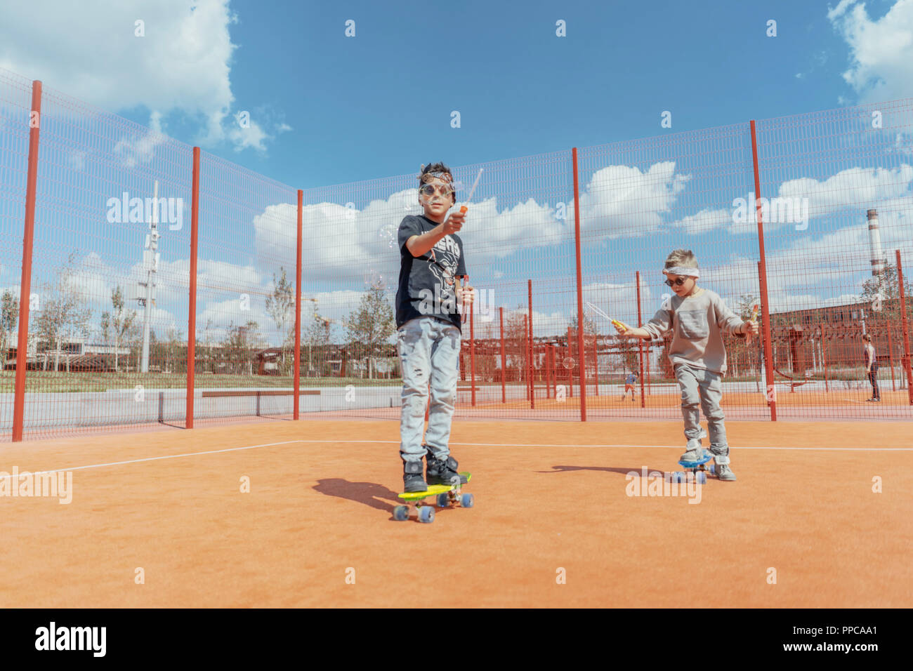 Young woman skating with her sons at playground. Happy family concept ...
