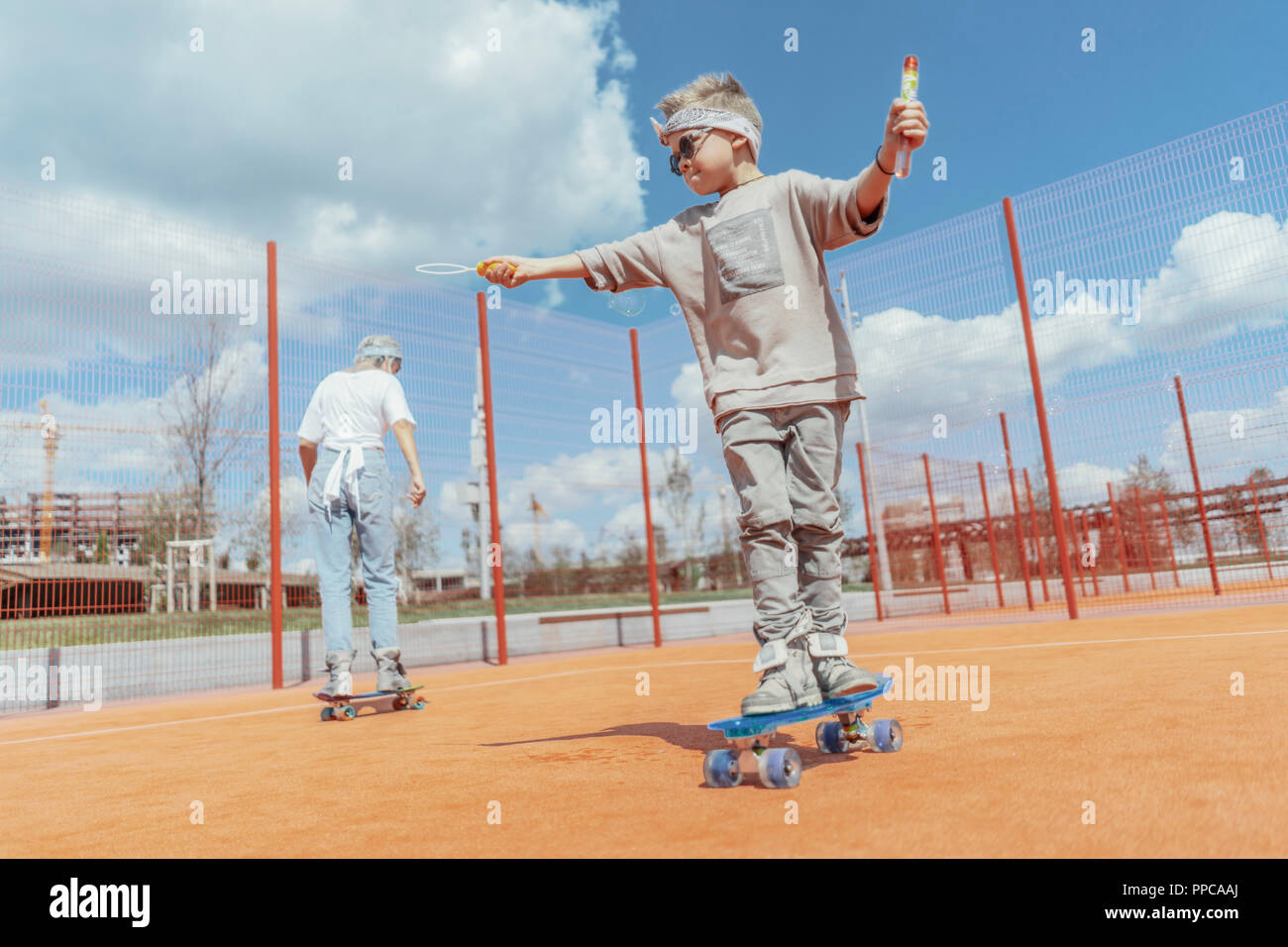Young woman skating with her sons at playground. Happy family concept ...