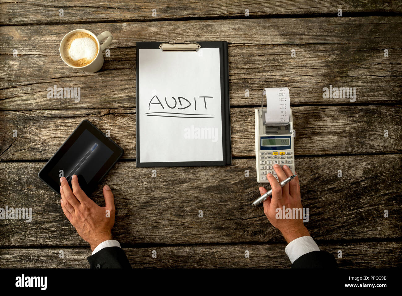 Top view of an auditor making calculations on adding machine with a ...