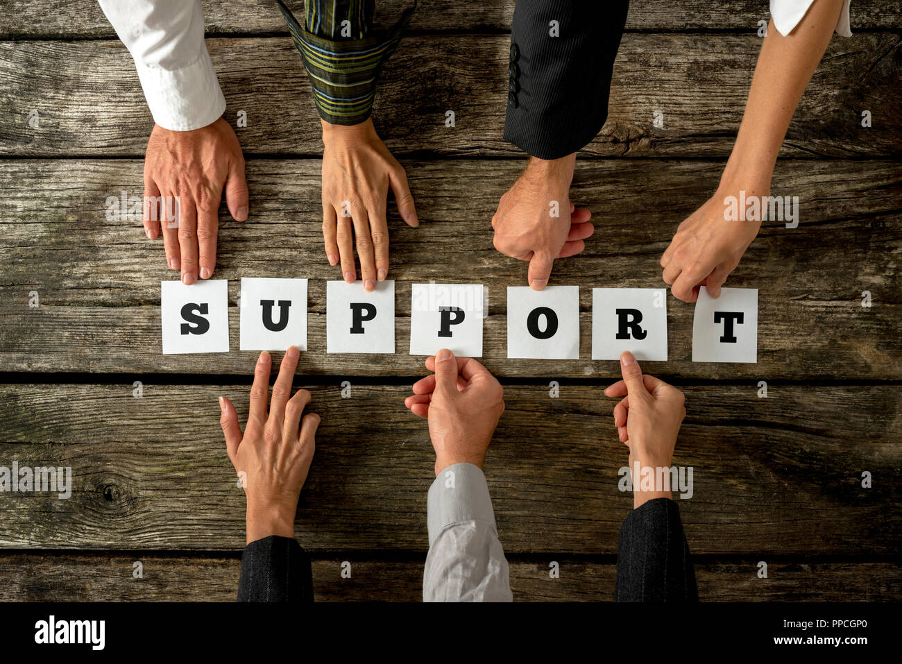 Seven business people holding white cards with letters to assemble the ...