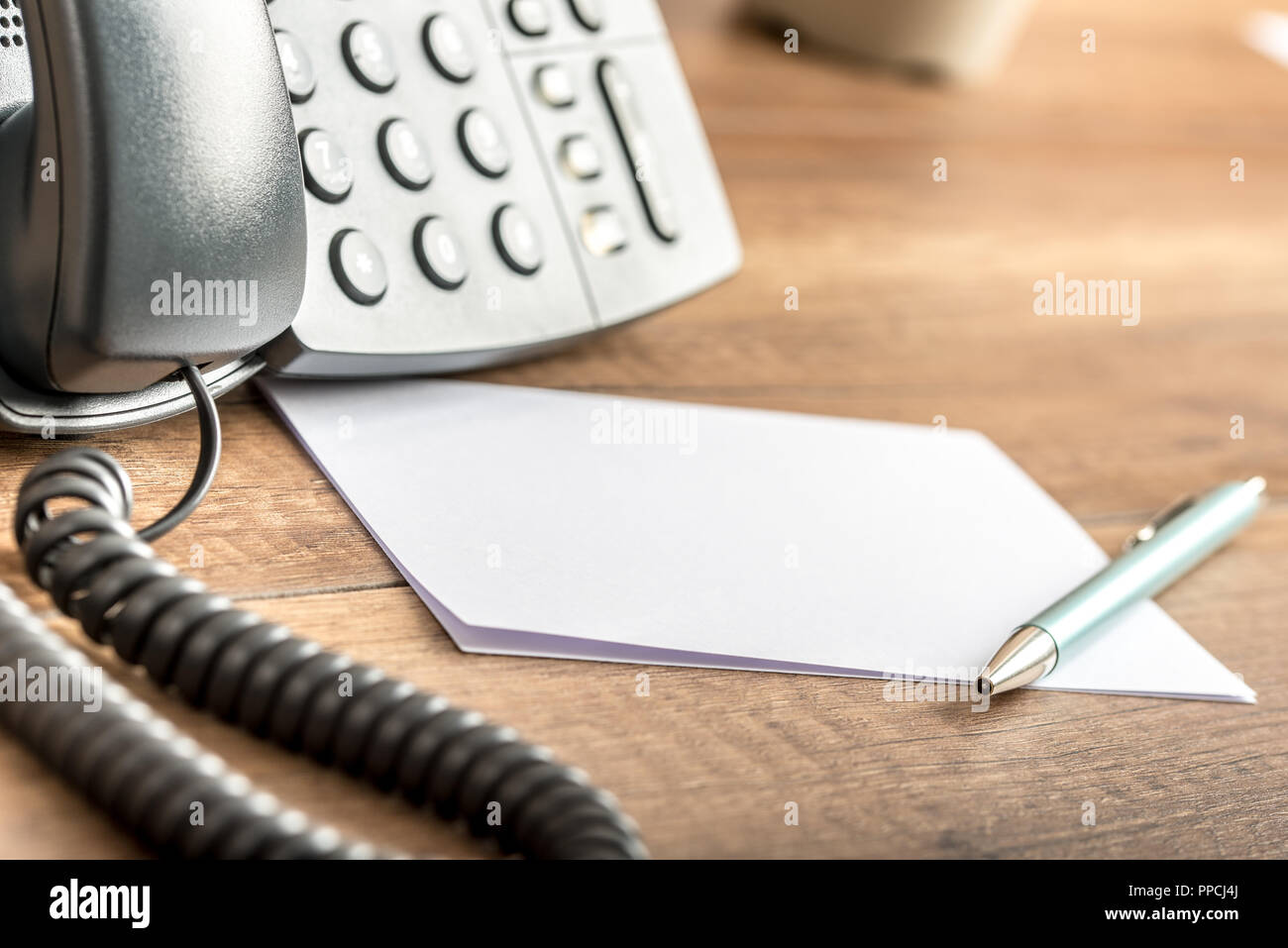 Pen lying on blank white note cards next to a landline telephone on a ...