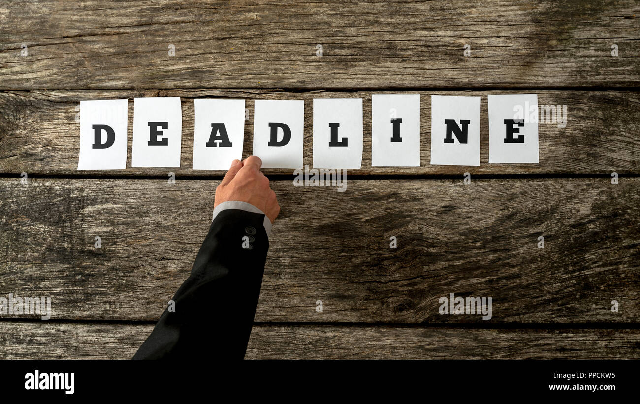 Overhead view of businessman or professor hand assembling a Deadline ...