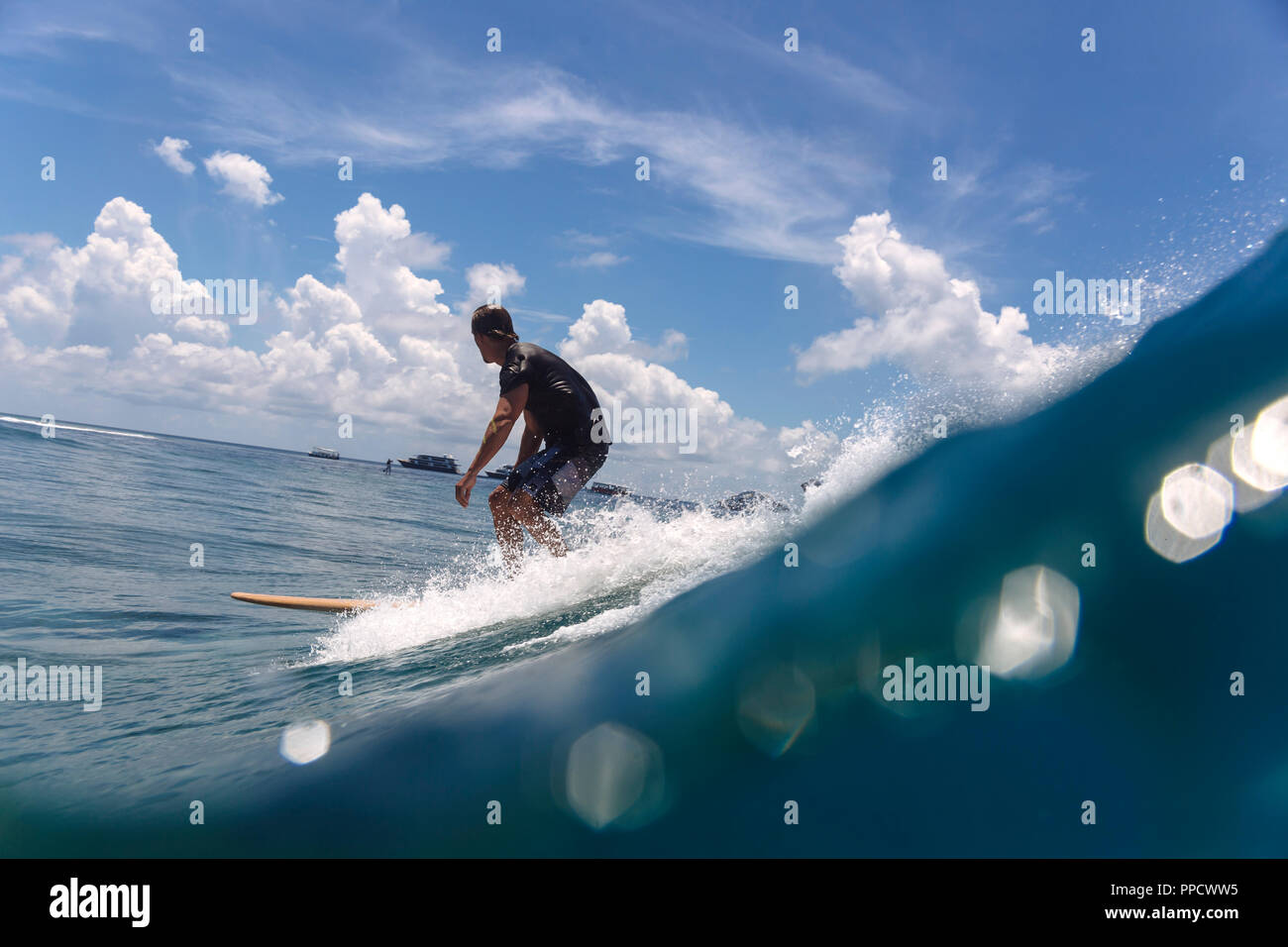 Male surfer riding wave against clouds, Male, Maldives Stock Photo - Alamy