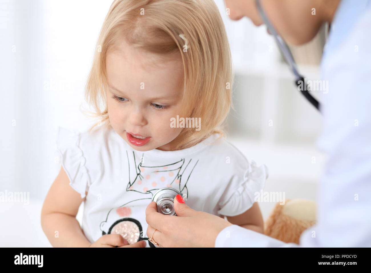 Doctor and patient baby in hospital. Little girl is being examined by ...