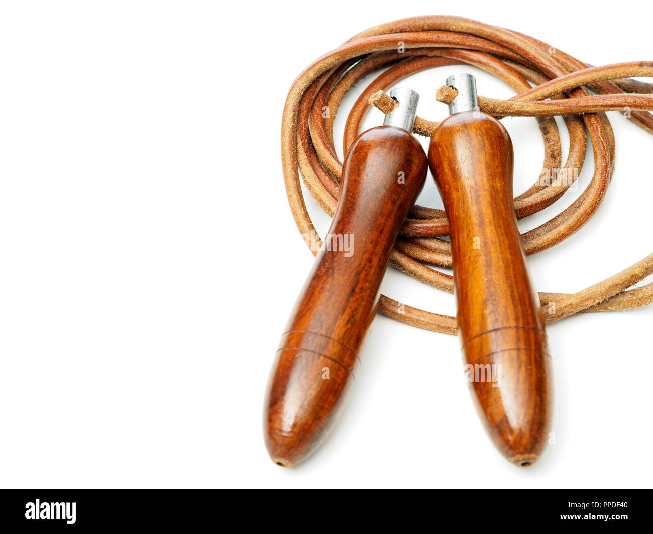 A coiled wooden handled leather skipping rope placed on a plain white ...