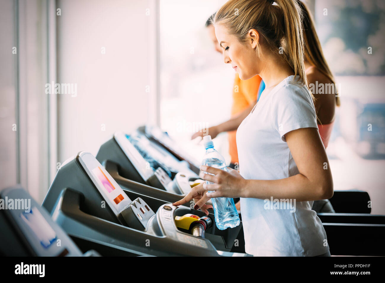 Young woman drinking water while exercising Stock Photo - Alamy