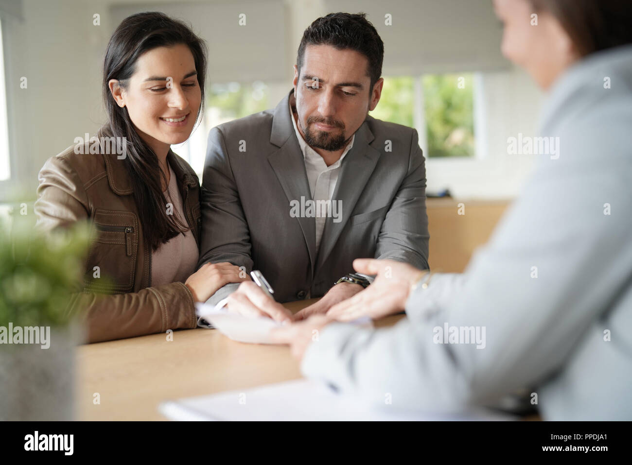 Couple in bank office signing loan agreement Stock Photo - Alamy
