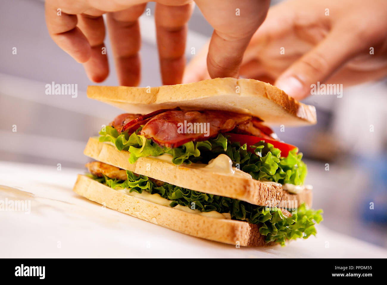Chef making sandwich in rustic style with bacon and fresh vegetables ...