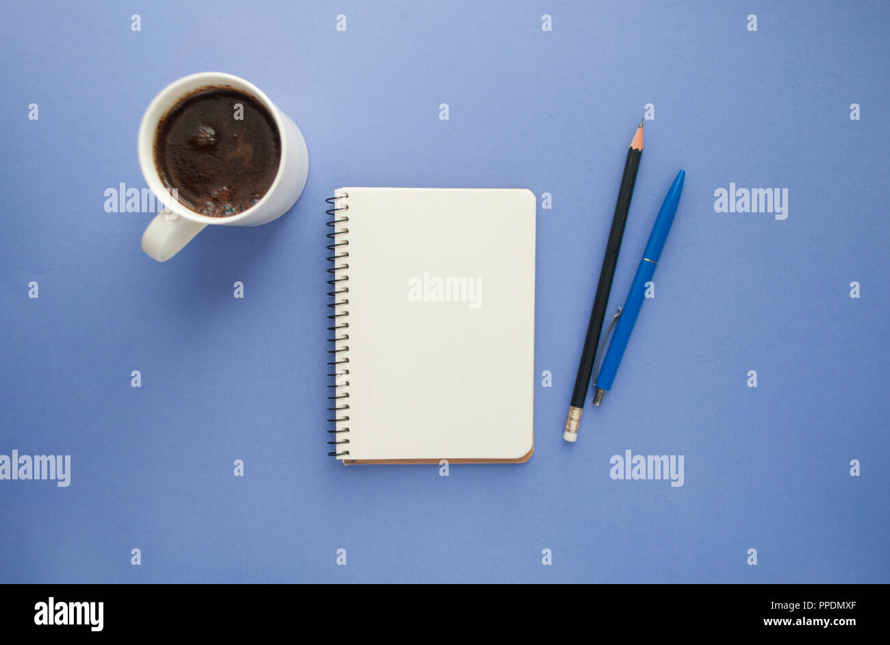 Flat lay of notepad, pens and a cup of coffee on purple background with ...