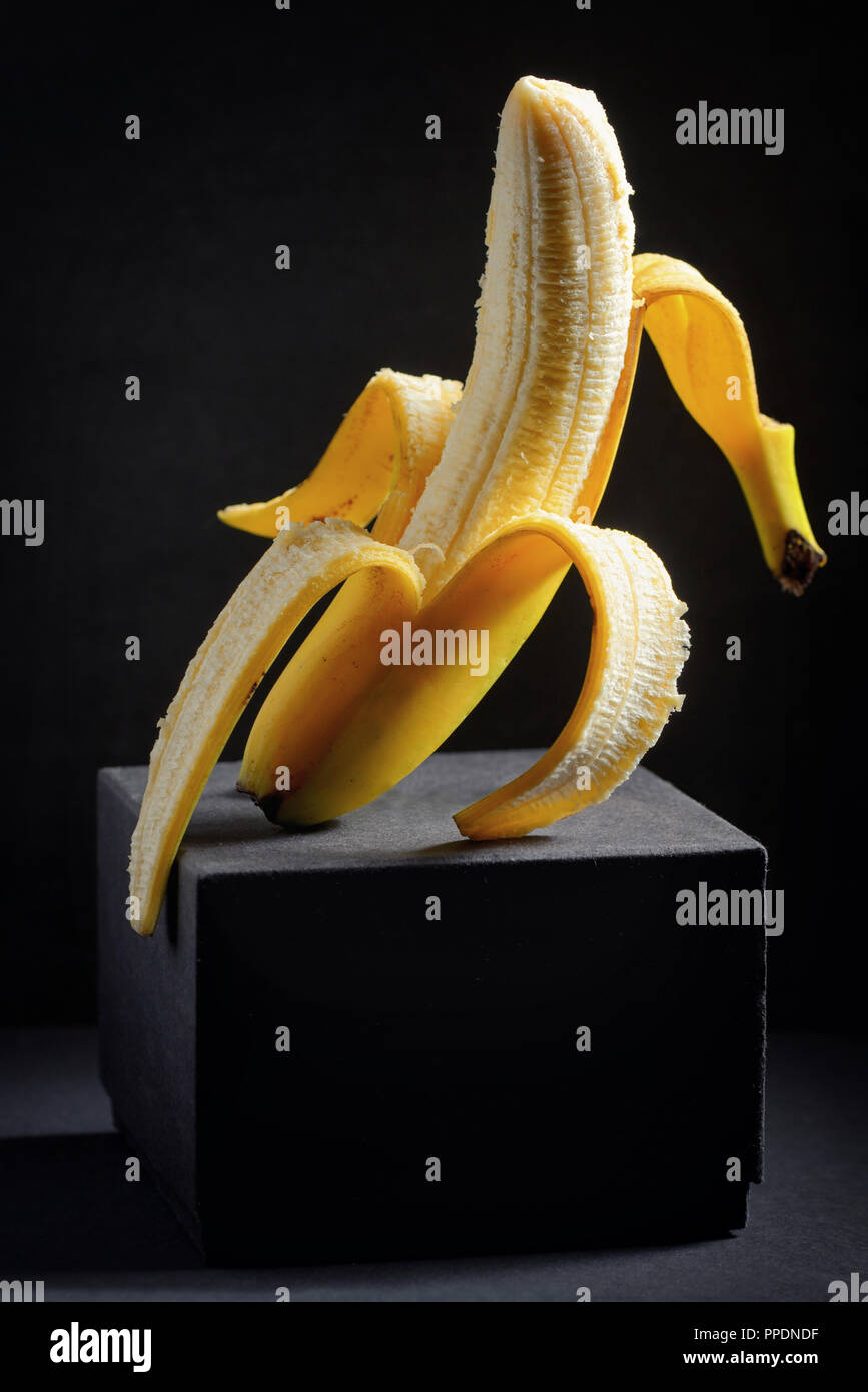 Vertical peeled banana on black background Stock Photo - Alamy