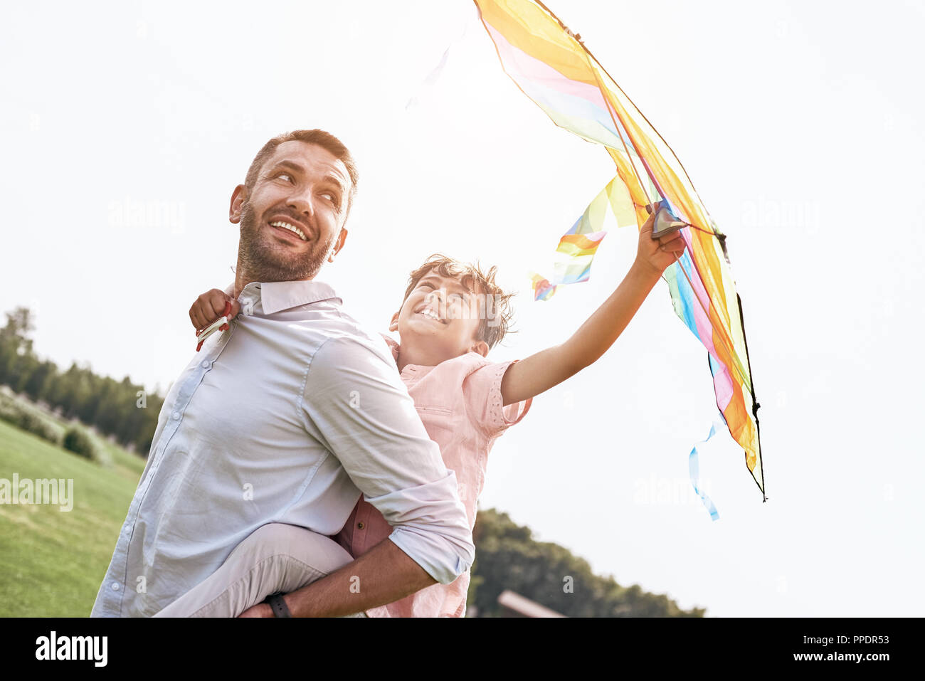 Weekend activities. Father carrying son on his back holding kite Stock ...