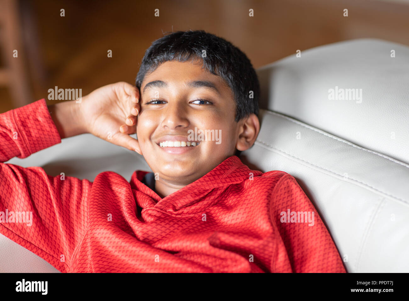 Portrait of a Smiling Young Boy Resting Against a Couch Stock Photo - Alamy