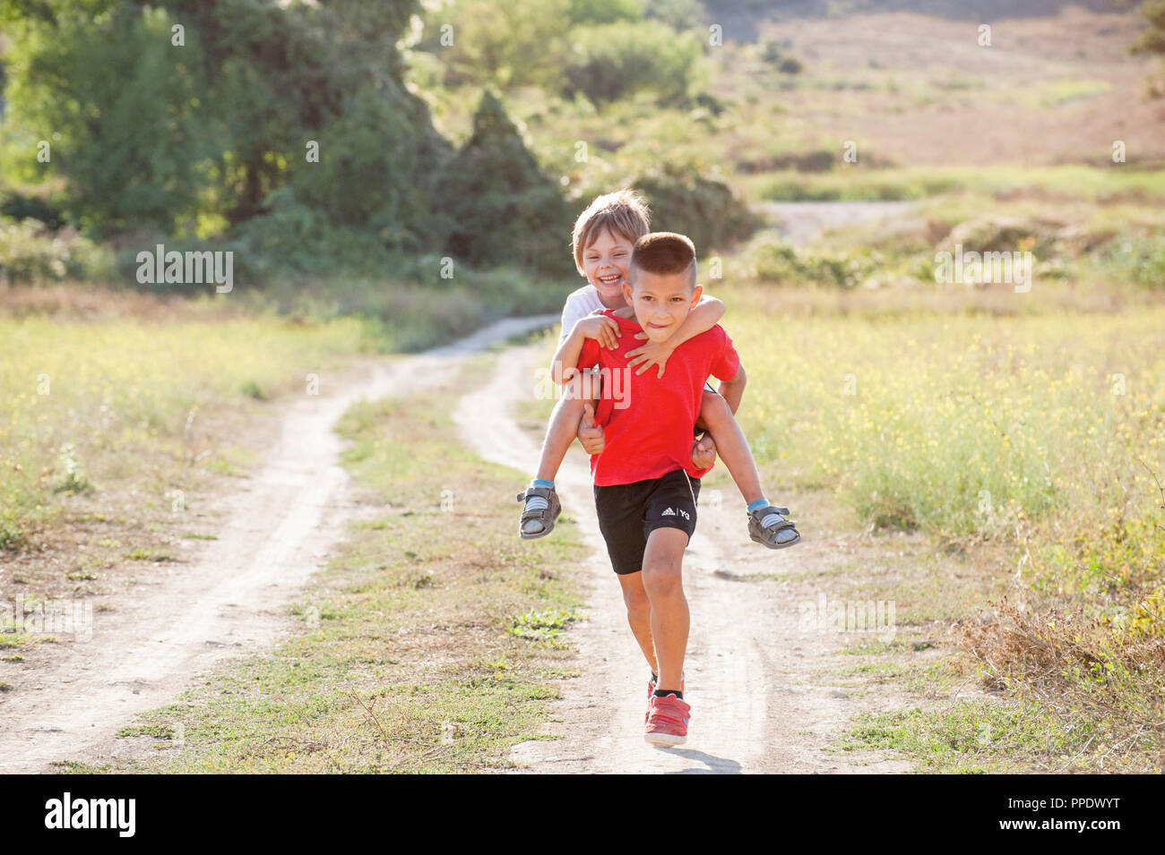 one happy healthy strong little boy carry small kid on his back running ...