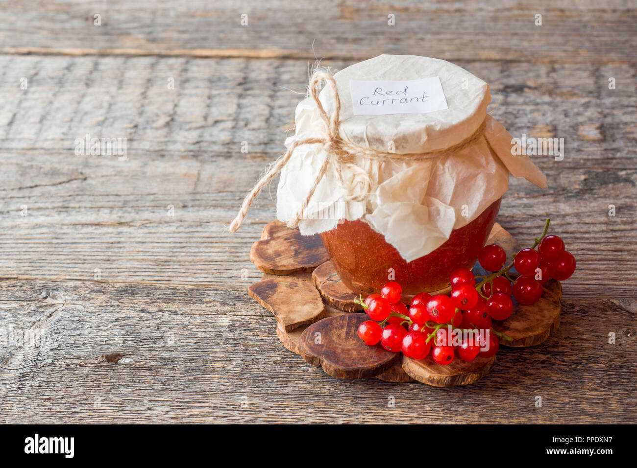 Useful currant jam in a glass jar. Fresh red currant on wooden ...
