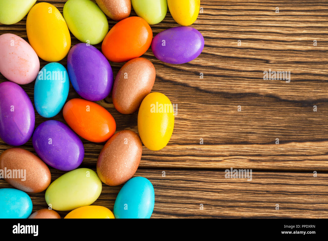 Brightly colored sugar coated fresh roasted almonds on wood with copy ...