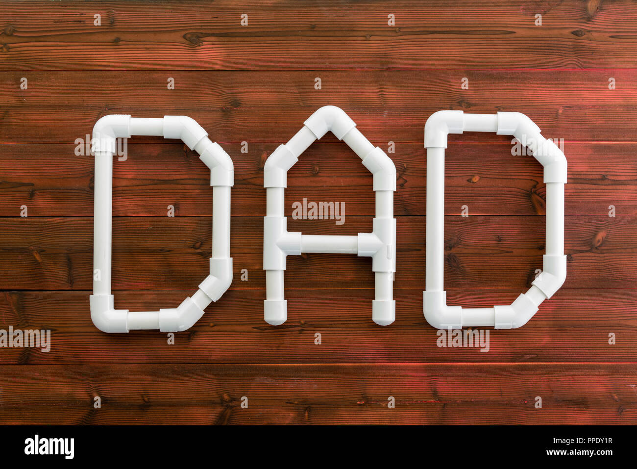 Word Dad formed of interlocked sections of white PVC pipes on a rustic ...