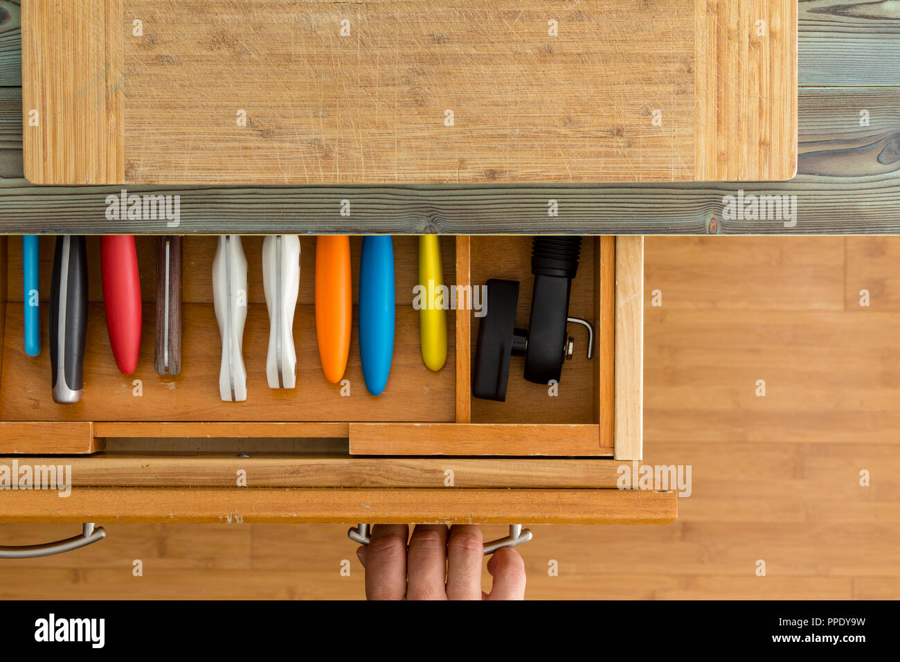 Man or chef opening a knife drawer in a kitchen in an overhead view of ...