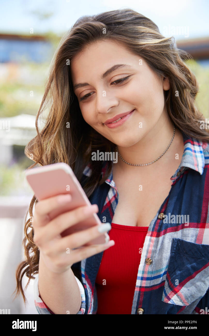 Female High School Student Checking Messages On Mobile Phone Outside ...