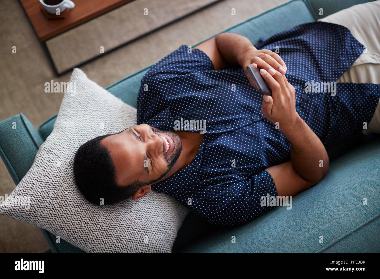 Overhead View Of Man Lying On Sofa At Home Using Mobile Phone Stock ...