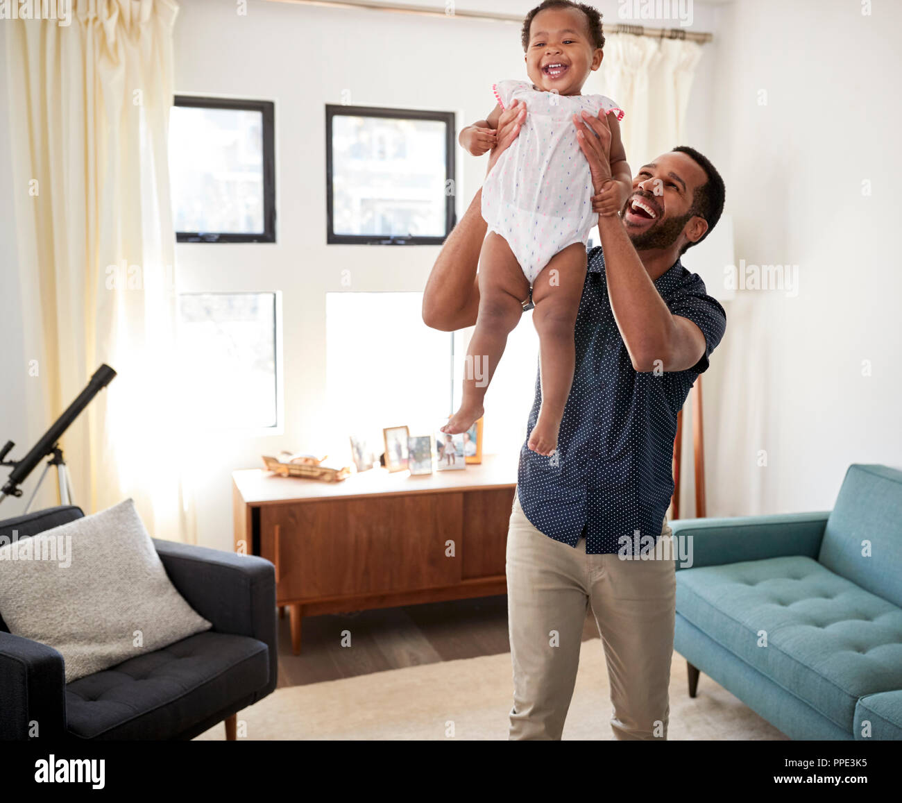 Father Standing In Lounge At Home Lifting Baby Daughter Into Air Stock ...