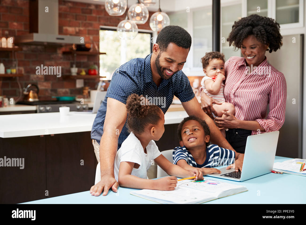 Father Helps Children With Homework Whilst Mother Holds Baby Stock ...