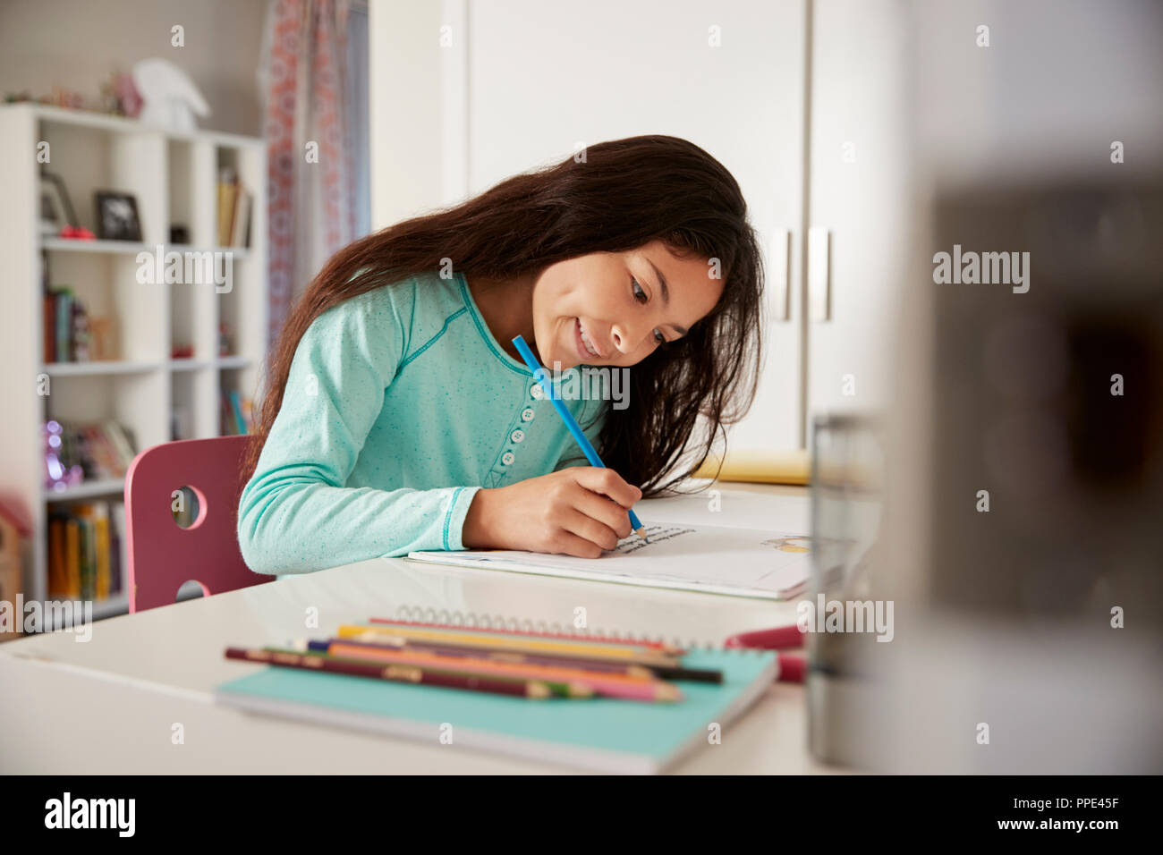 Young Girl Sitting At Desk In Bedroom Doing Homework Stock Photo - Alamy