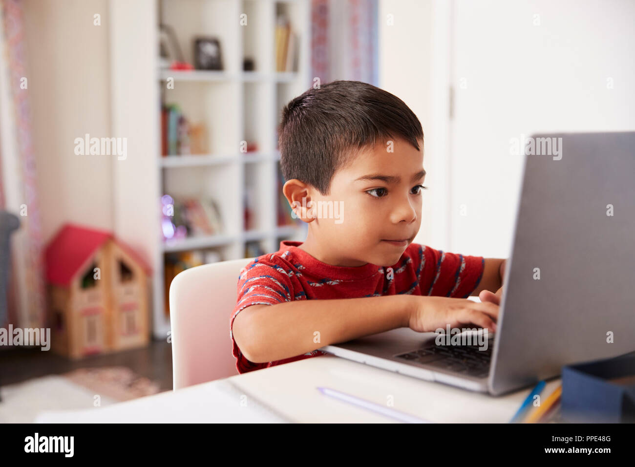 Young Boy Sitting At Desk In Bedroom Using Laptop To Do Homework Stock ...