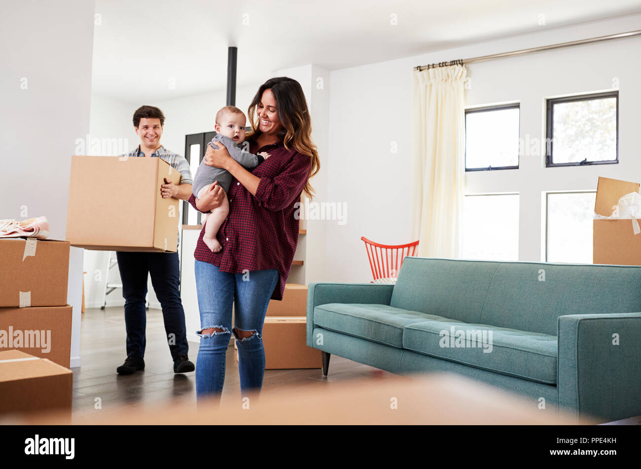 Family With Baby Carrying Boxes Into New Home On Moving Day Stock Photo ...