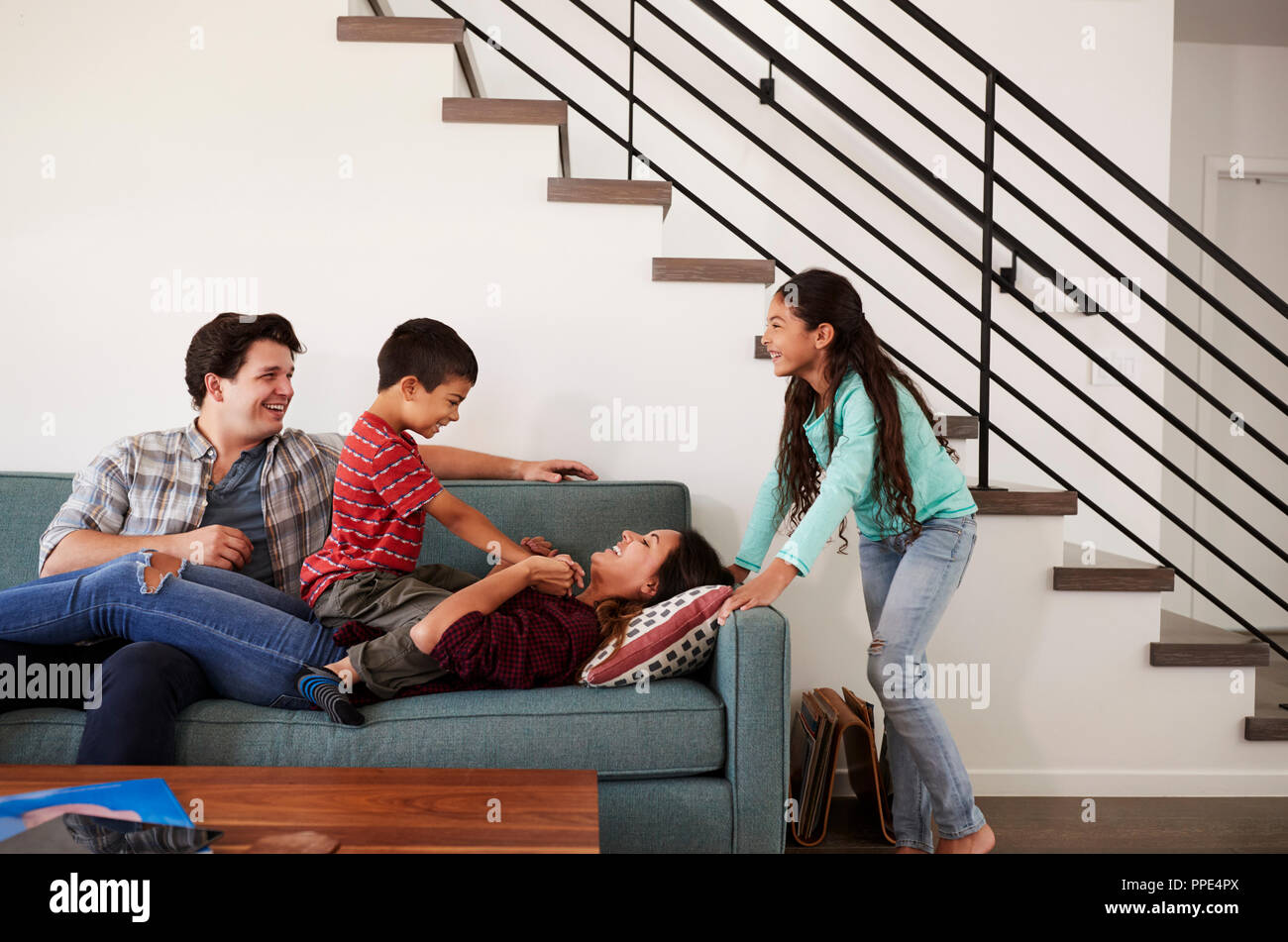 Family Having Fun Lying On Sofa At Home Together Stock Photo - Alamy