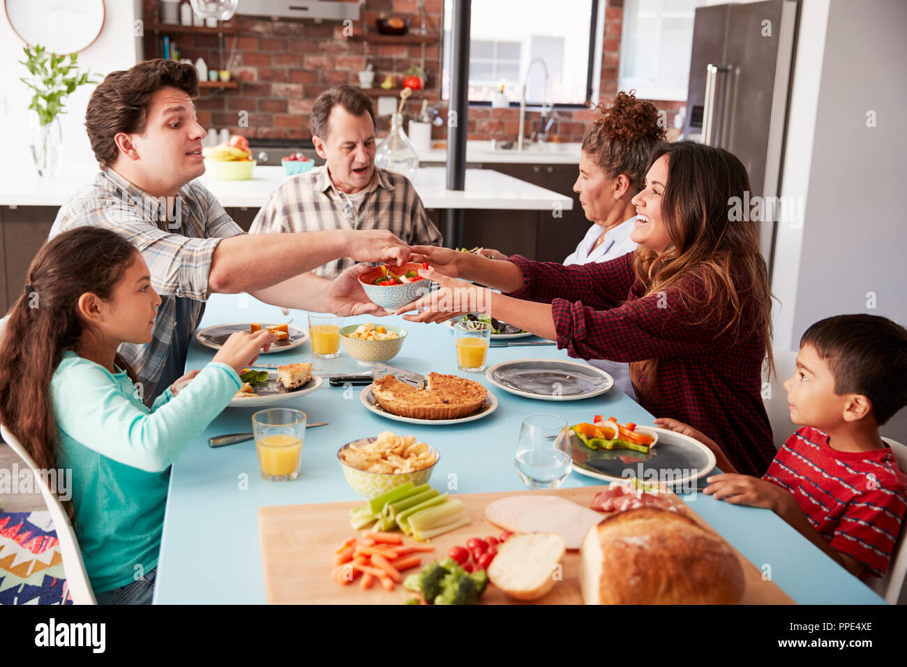 Multi Generation Family Enjoying Meal Around Table At Home Together ...