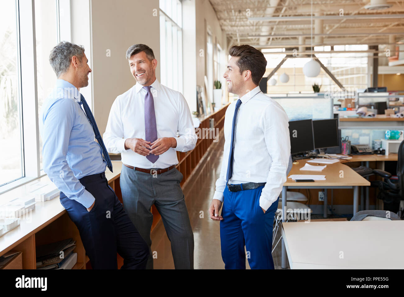 Three male corporate business colleagues chatting at work Stock Photo ...