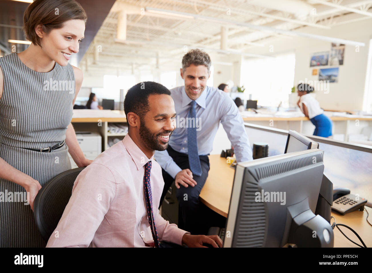 Three Happy Colleagues Looking At A Computer Screen Together Stock