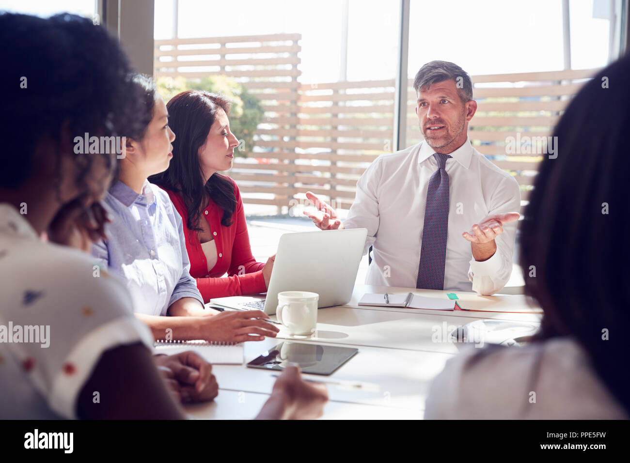 Male manager sits talking to colleagues in a meeting room Stock Photo ...