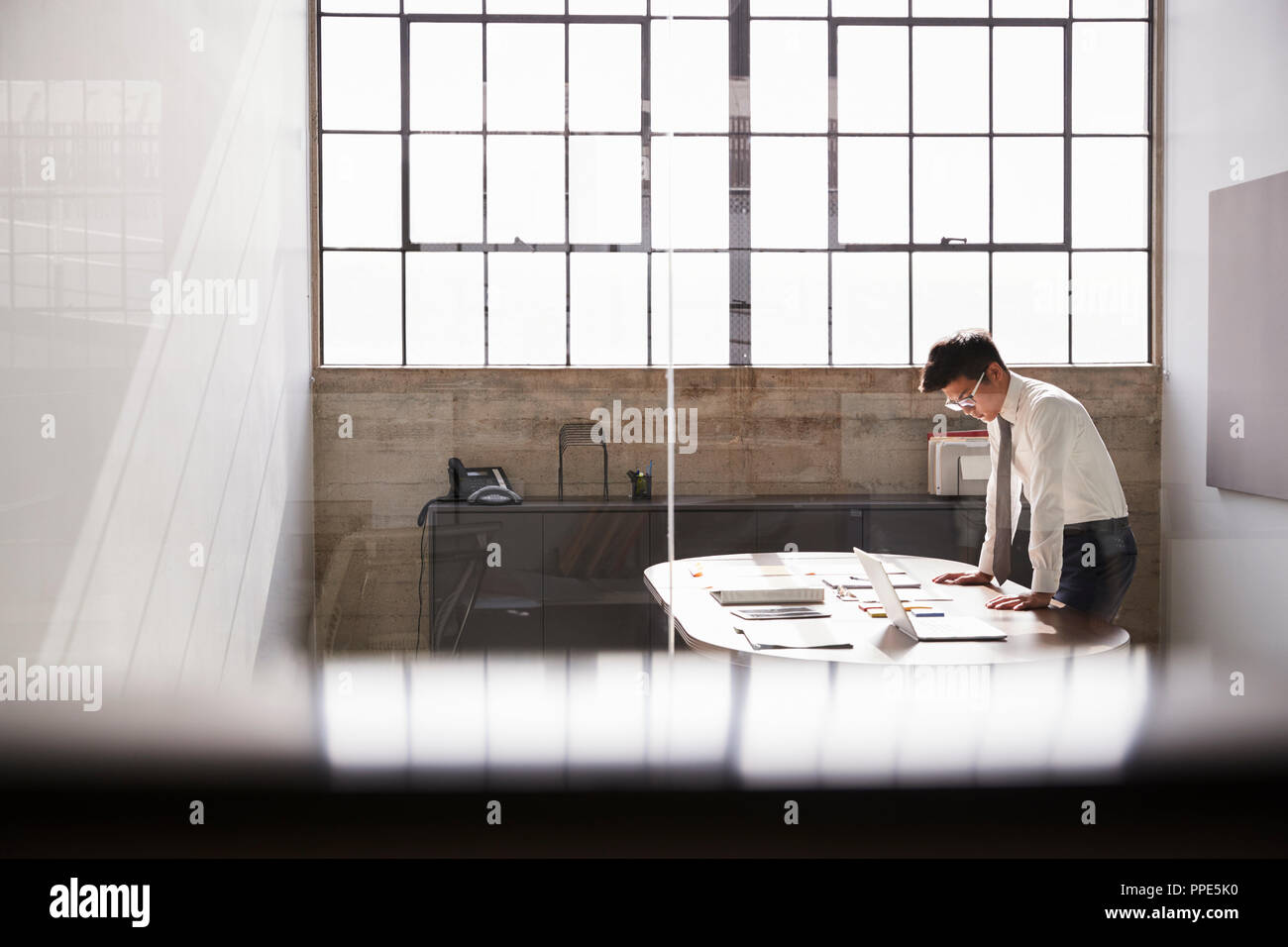 Businessman working alone in an office, seen through window Stock Photo ...