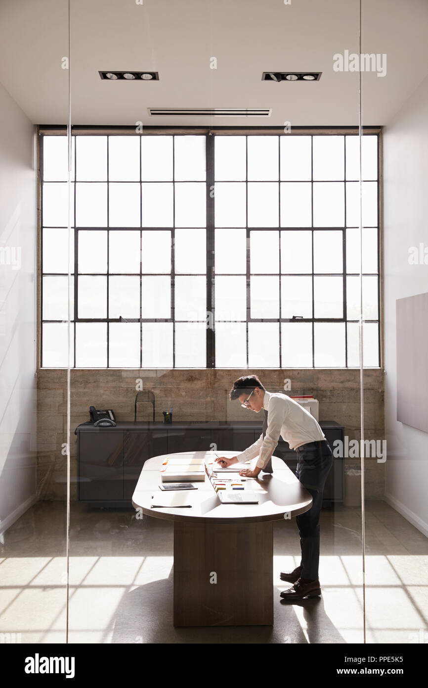 Businessman stands working alone in an office, vertical Stock Photo - Alamy