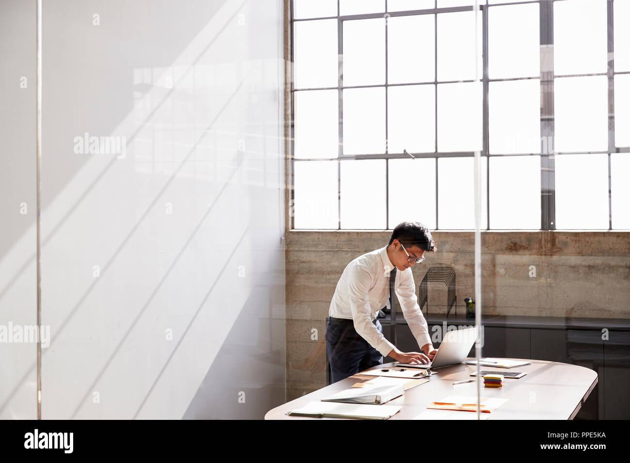 Businessman working alone in a office, seen through window Stock Photo ...