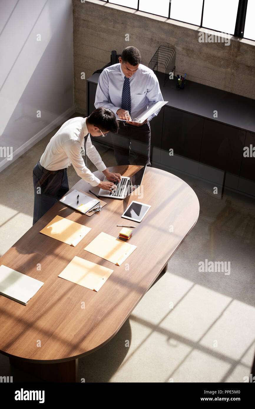 Two businessmen stand working at a desk in an office Stock Photo - Alamy