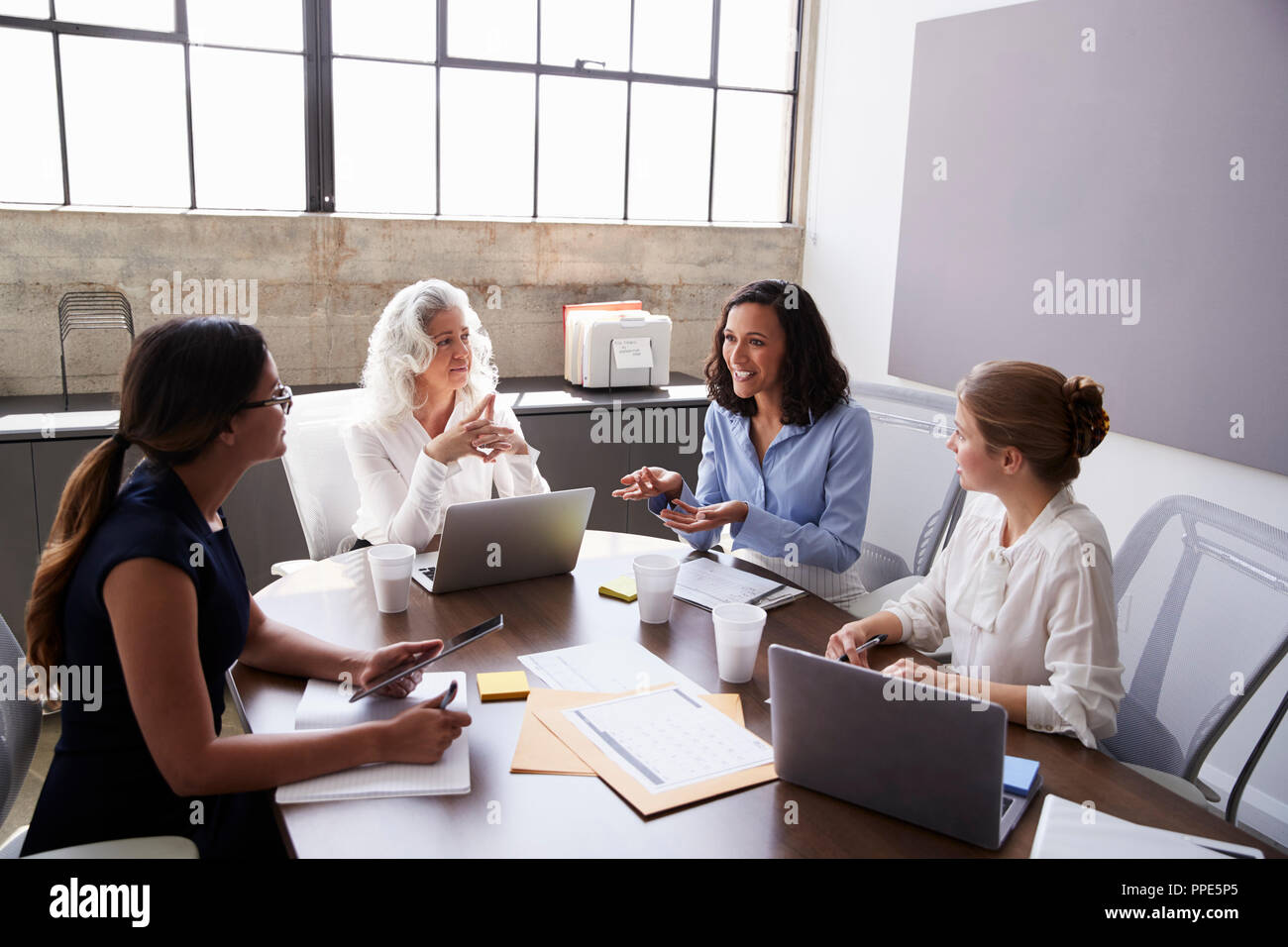 Four businesswomen in discussion in a meeting room Stock Photo - Alamy
