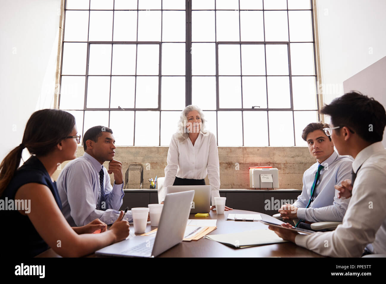 Female manager stands listening at team brainstorm meeting Stock Photo ...