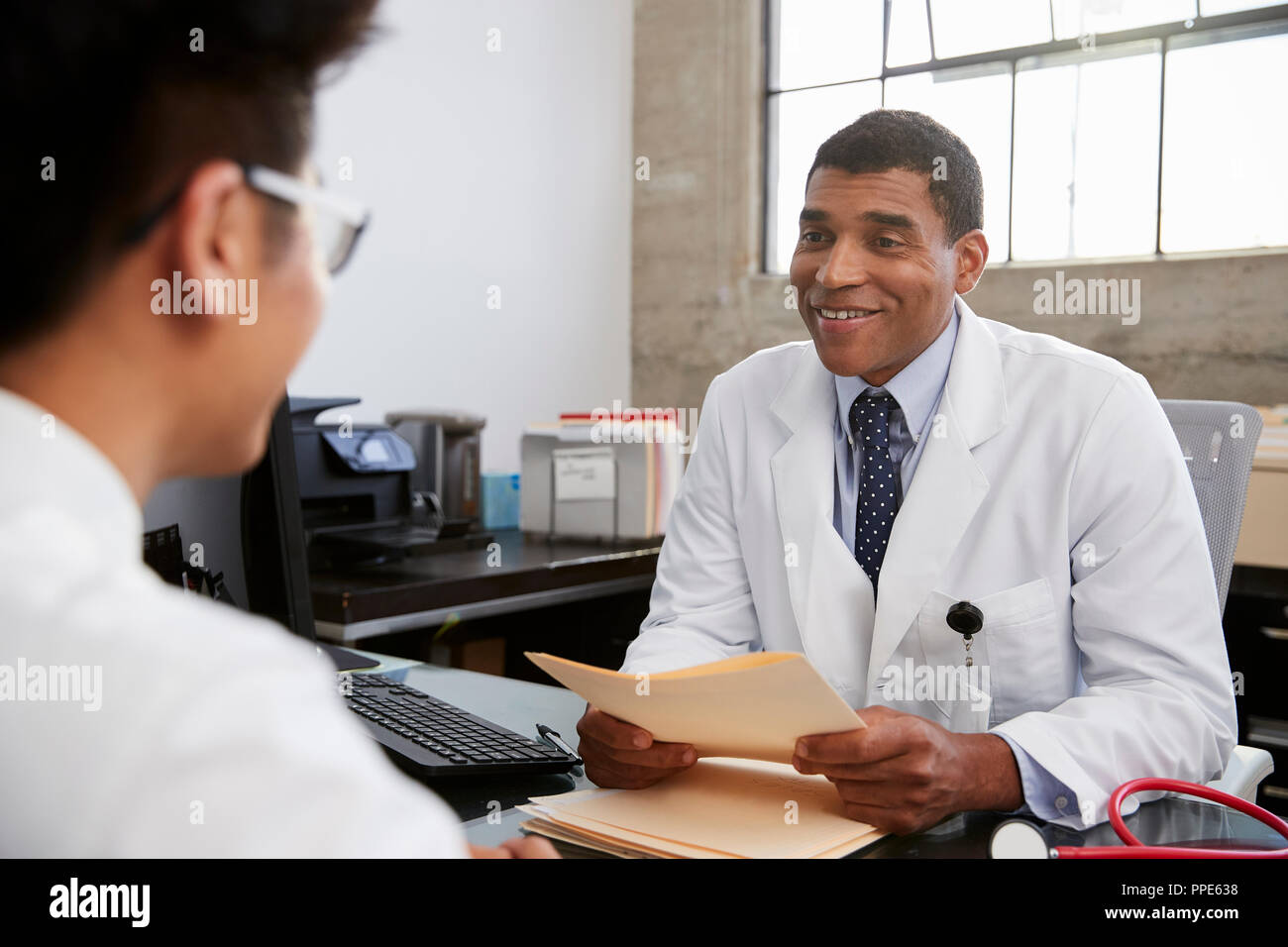 Mixed race male doctor holding documents in patient meeting Stock Photo ...