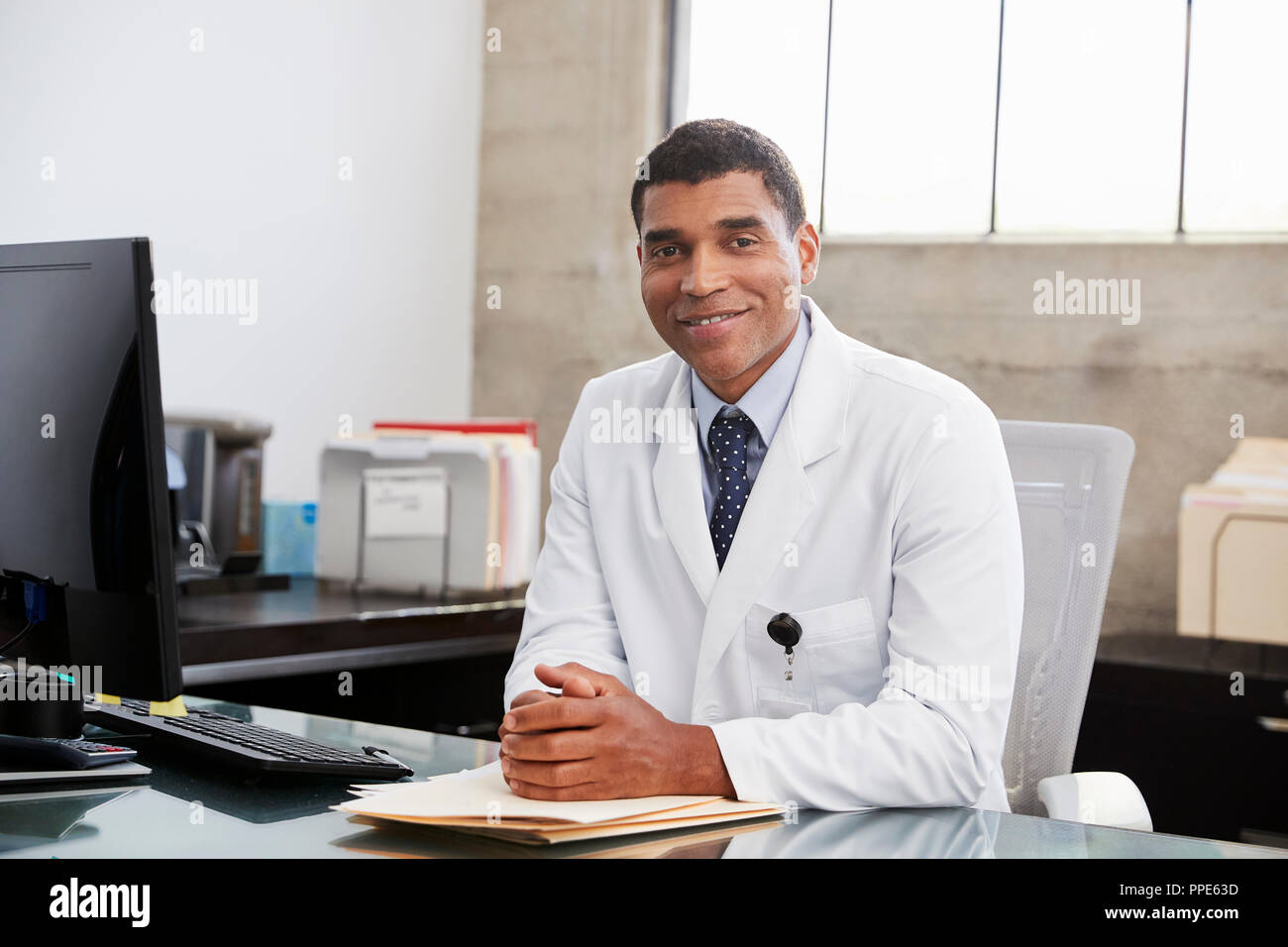 Mixed race male doctor at desk, portrait Stock Photo - Alamy