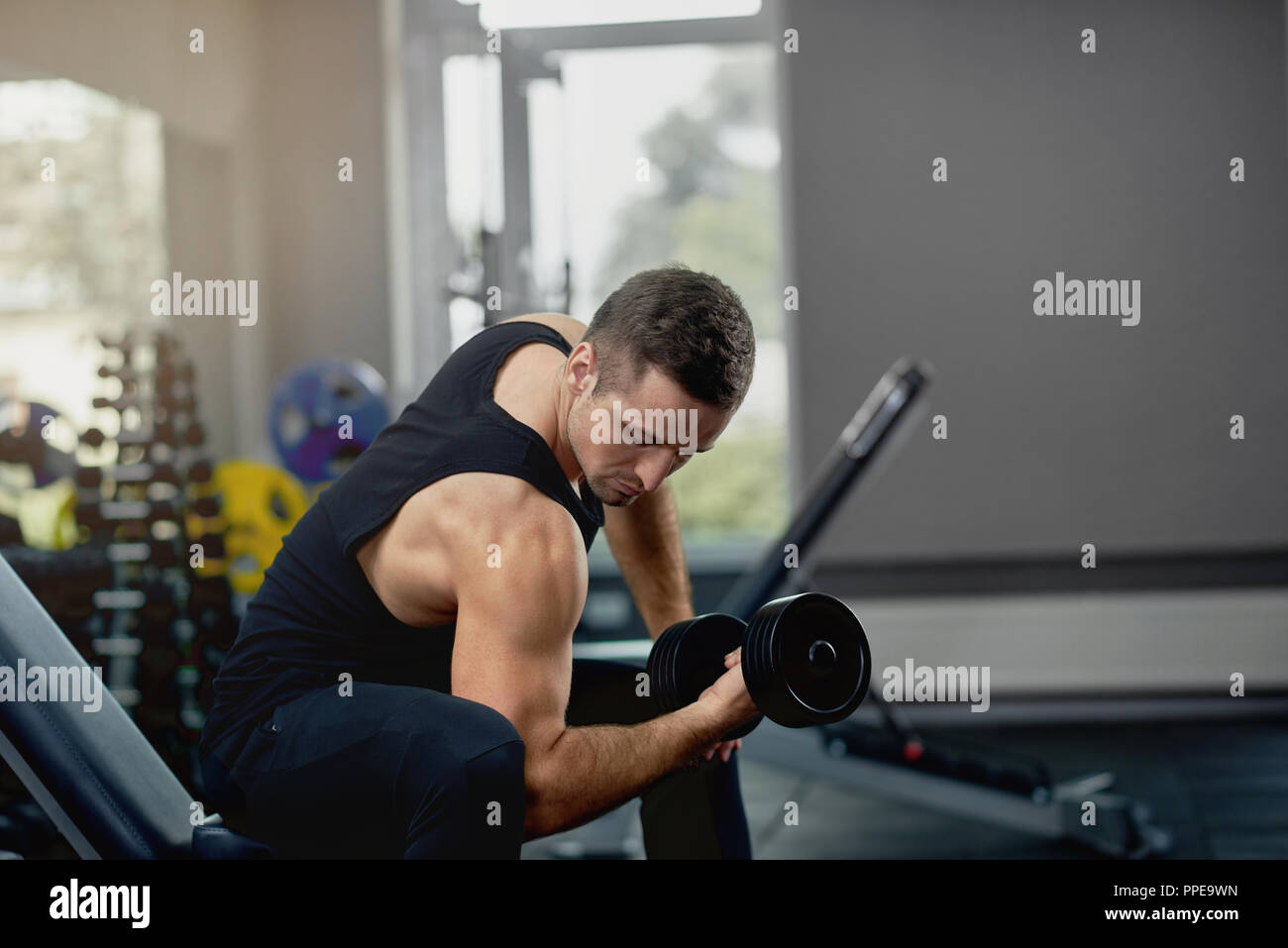 Handsome sporty man flexing muscles with barbell in dark gym. Sport ...