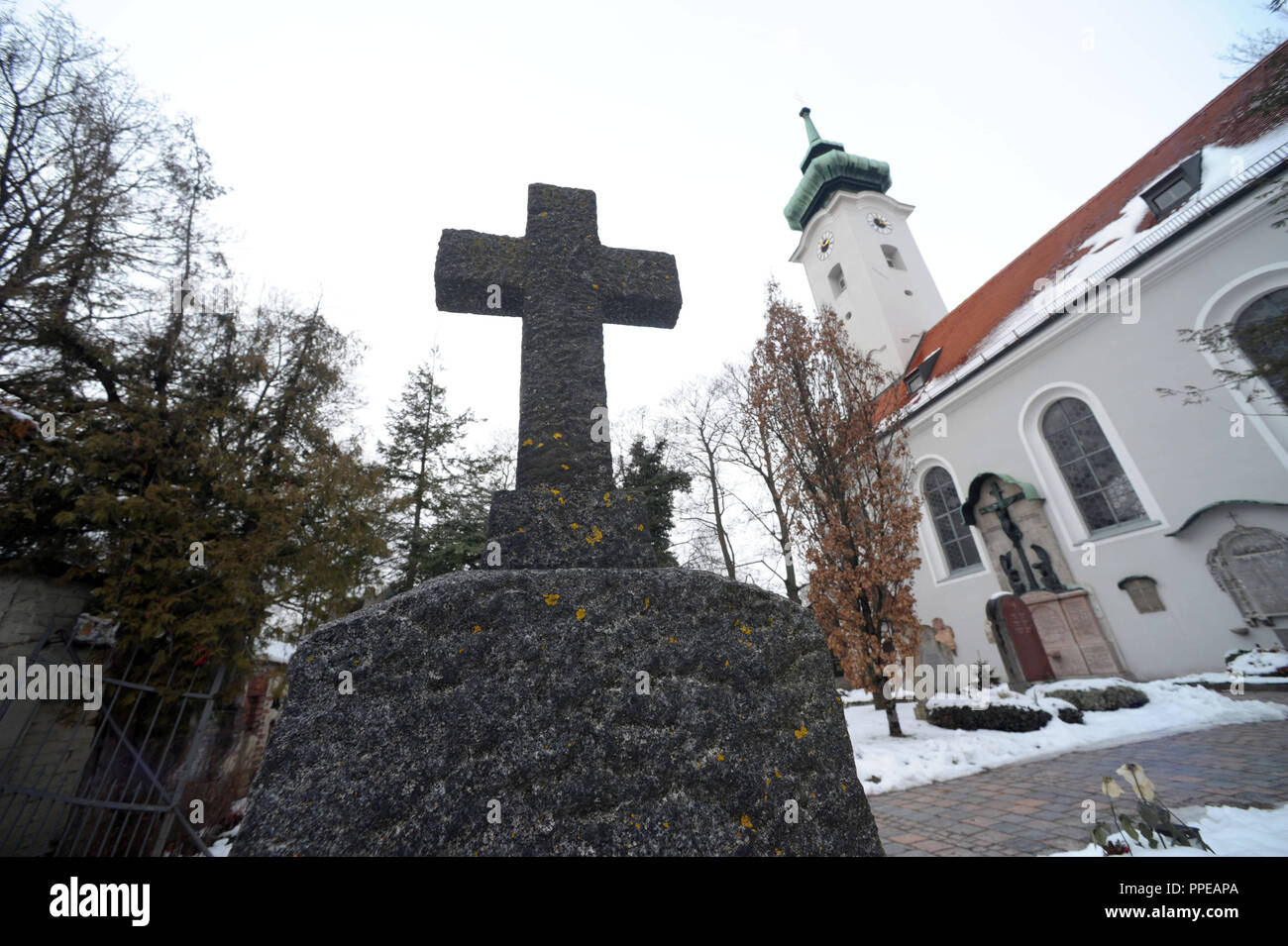 A stone grave cross and the St. Georg Church in the old Bogenhausen ...