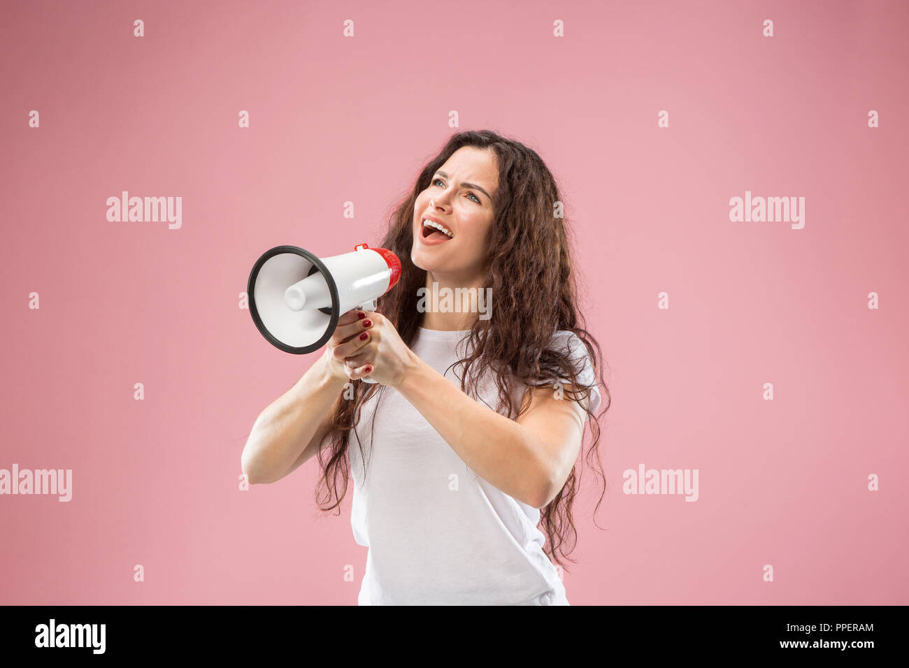 Woman making announcement with megaphone at pink studio. Human facial ...