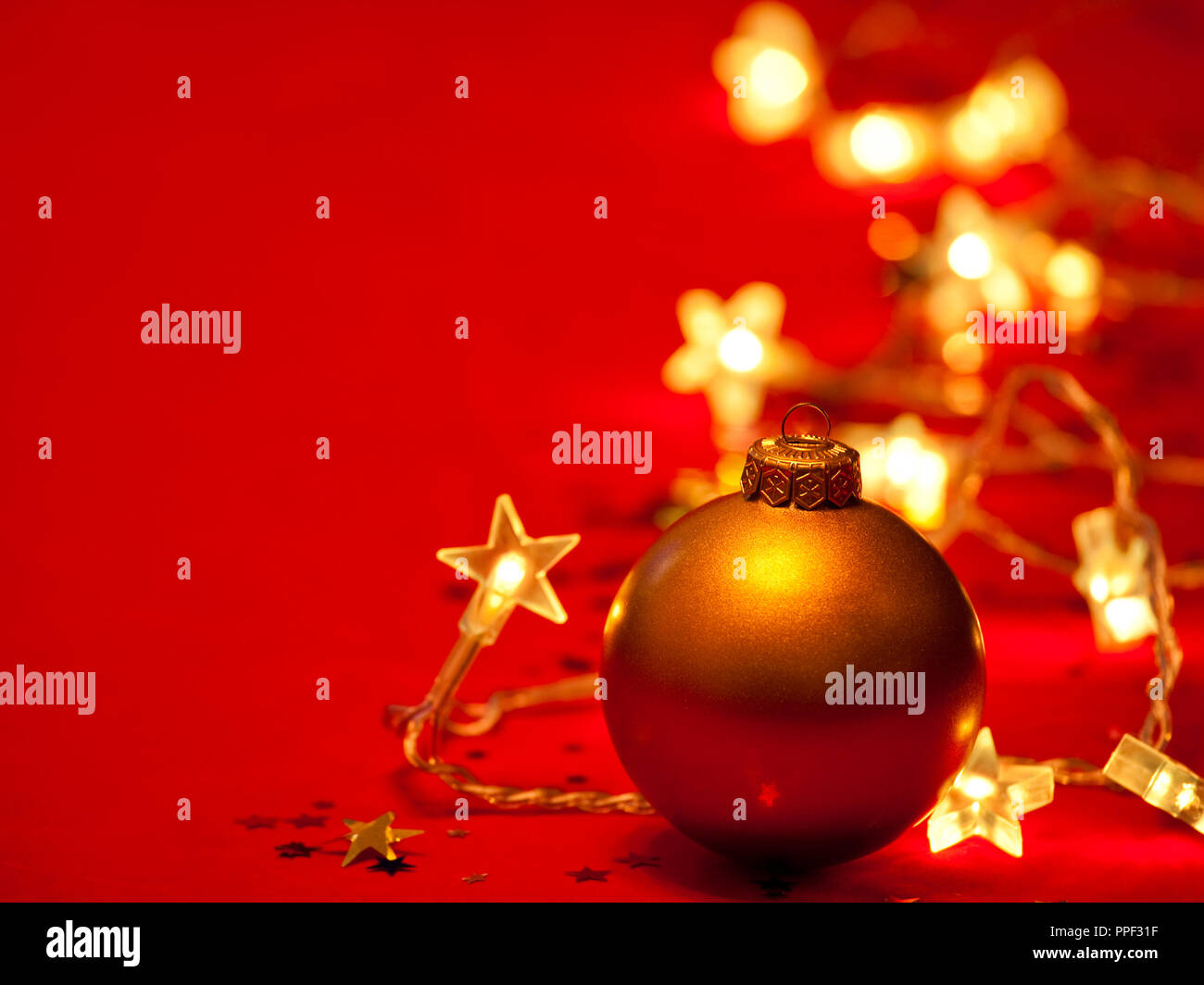 Golden Christmas bauble with star-shaped lights on red background ...
