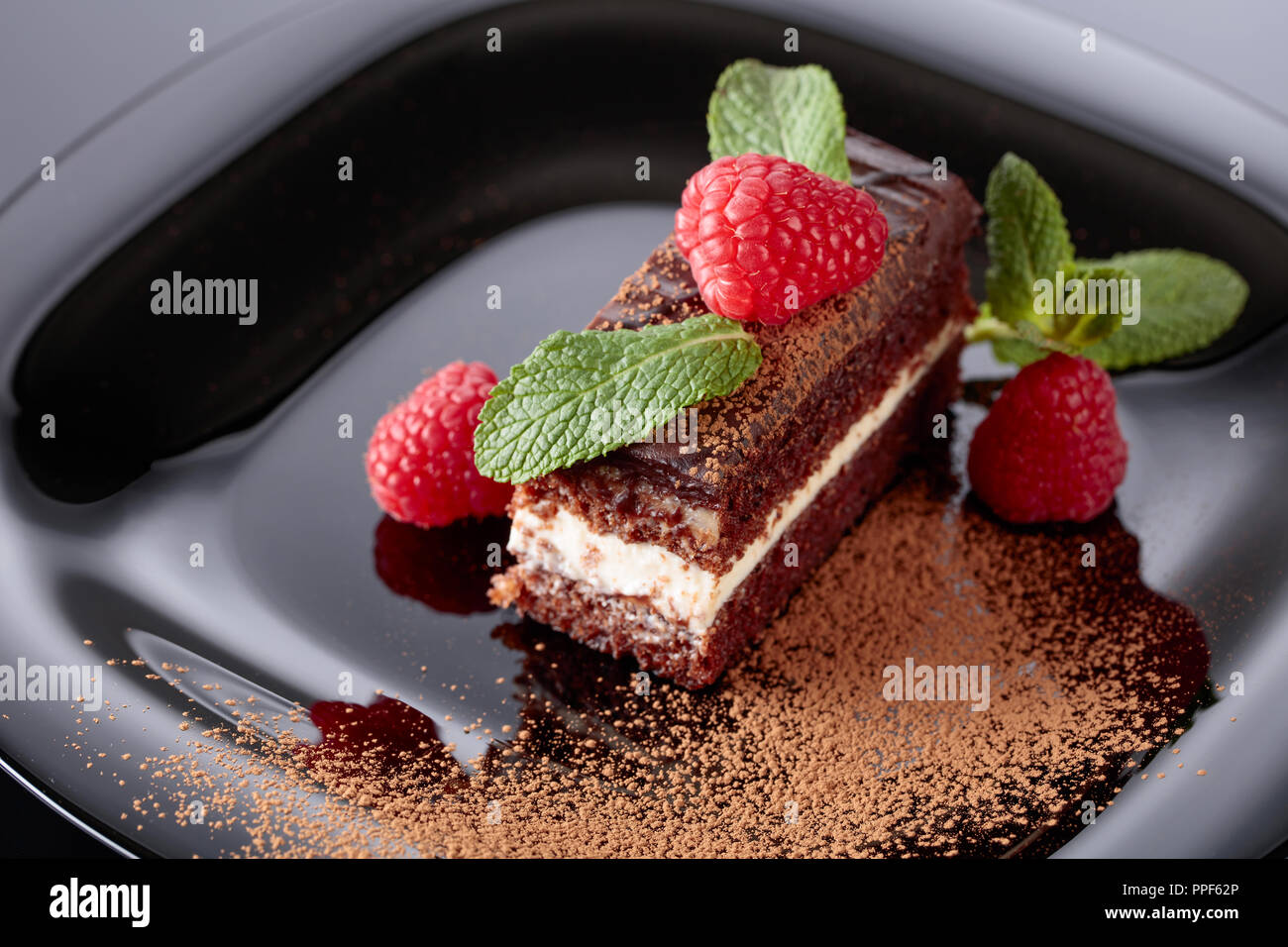 Chocolate cake with raspberry and mint on a black plate Stock Photo - Alamy