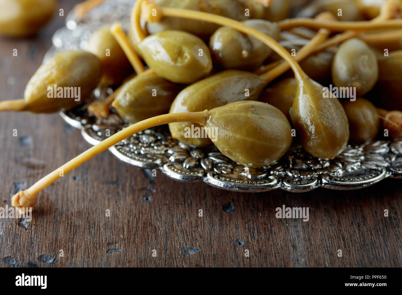 Pickled caper berries in metal dish . Edible fruits of Capparis ...
