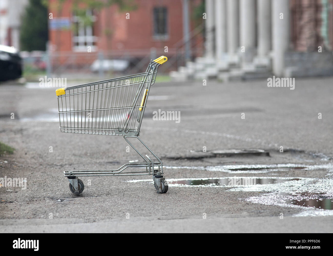 Grocery trolley stands alone on the street on the wet asphalt Stock ...